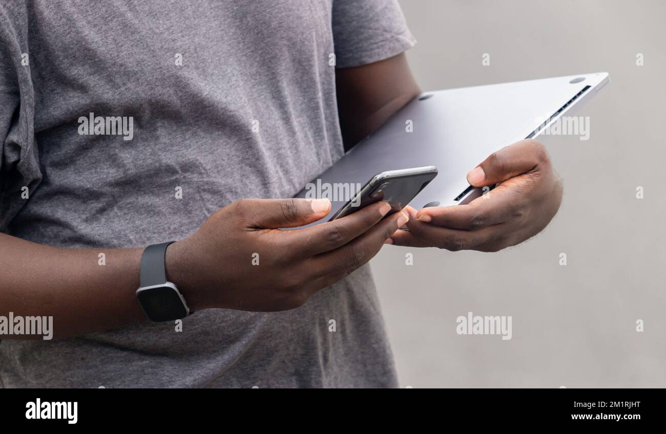 African man hand reading text message on mobile phone while in urban ...