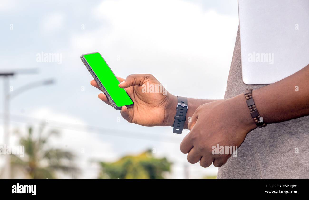 African man hand reading text message on mobile phone while in urban ...