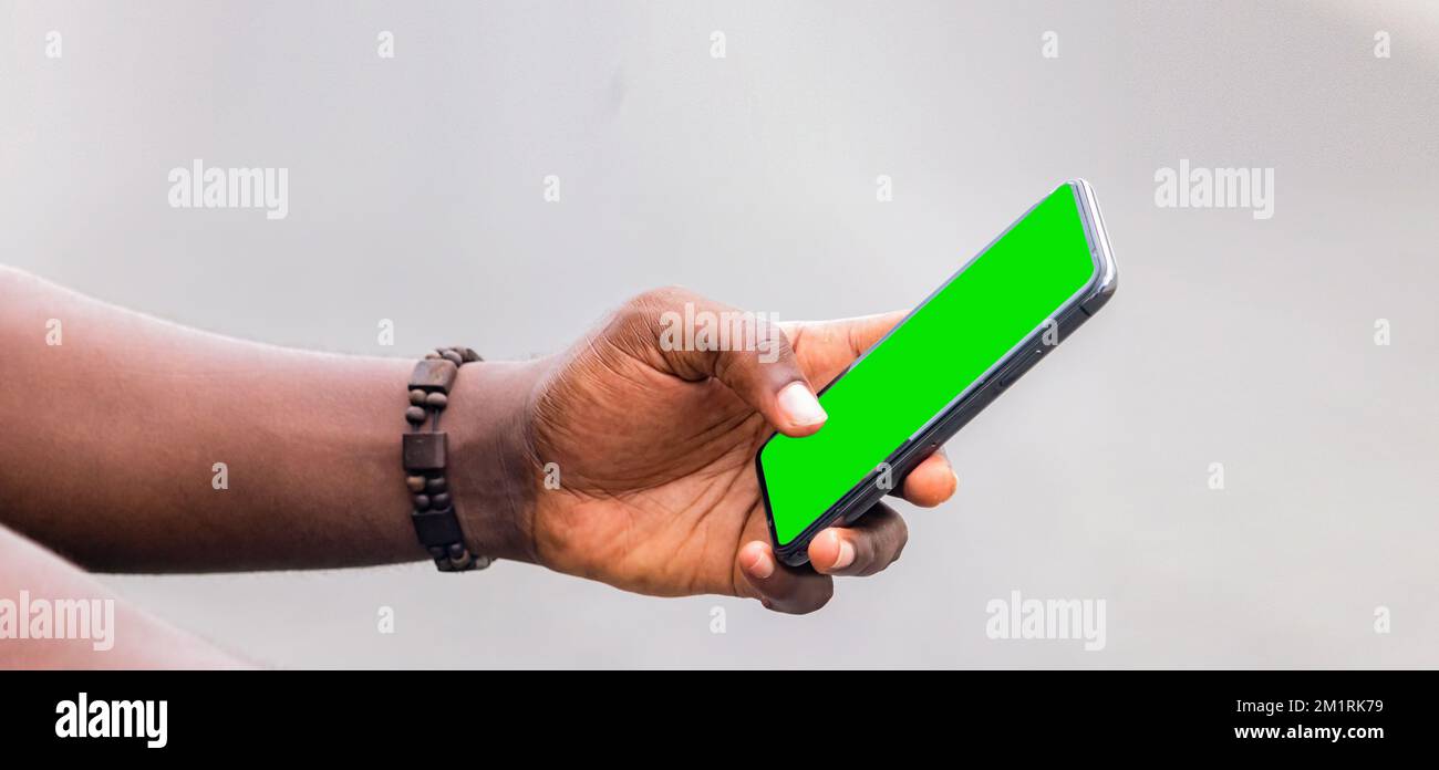 African man hand reading text message on mobile phone while in urban ...
