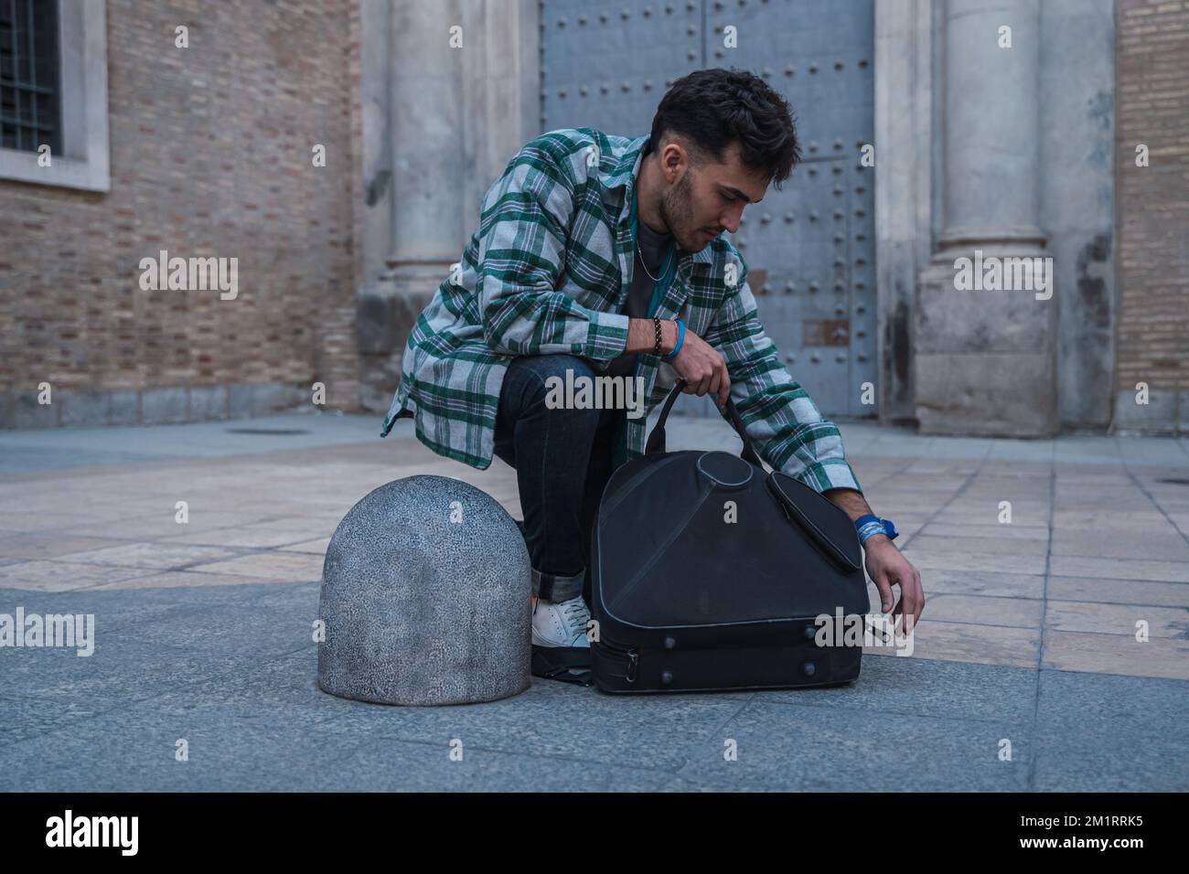 Male musician opening his suitcase on the street to start playing his ...