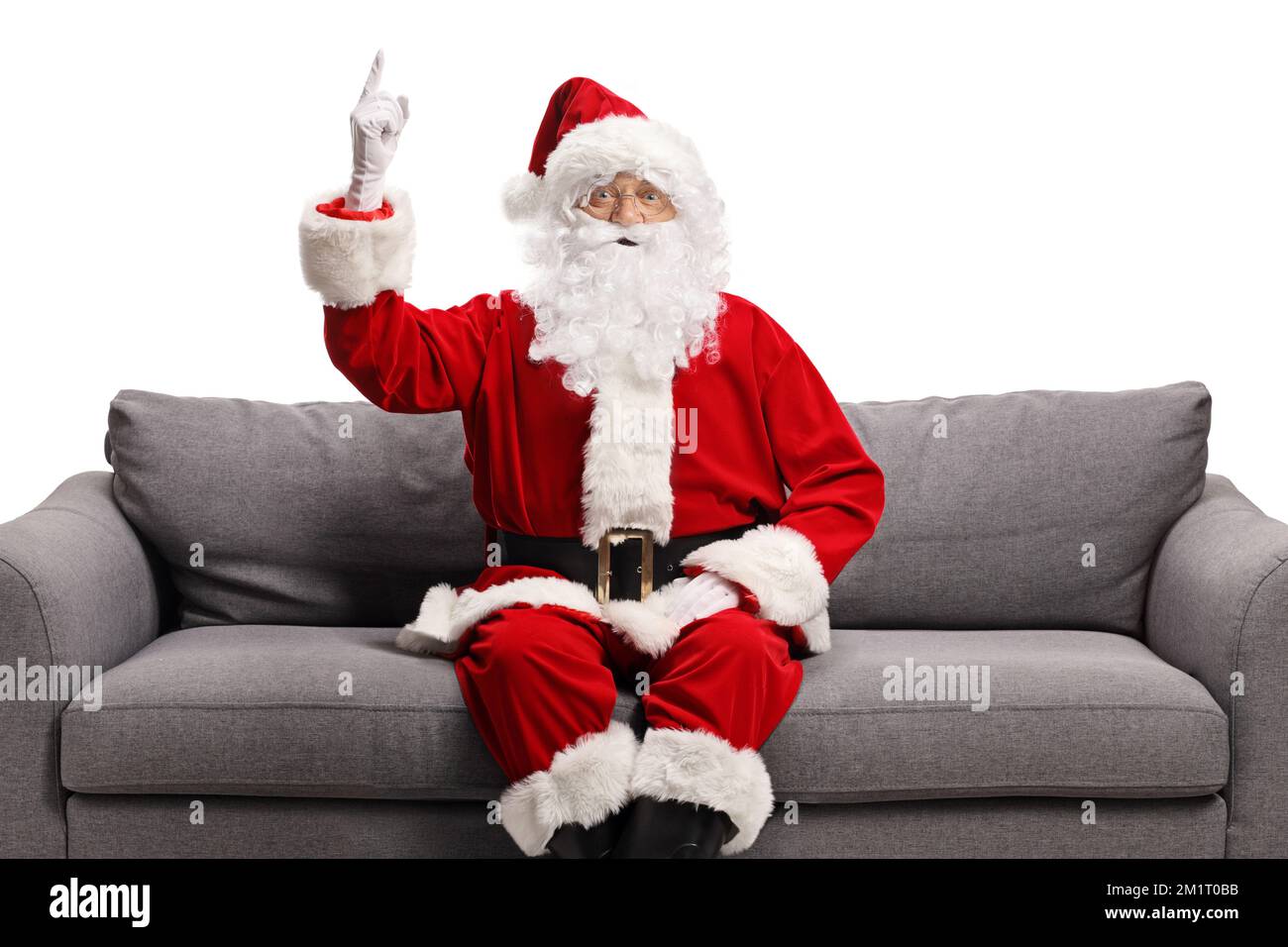 Santa claus sitting on a sofa and pointing up isolated on white ...