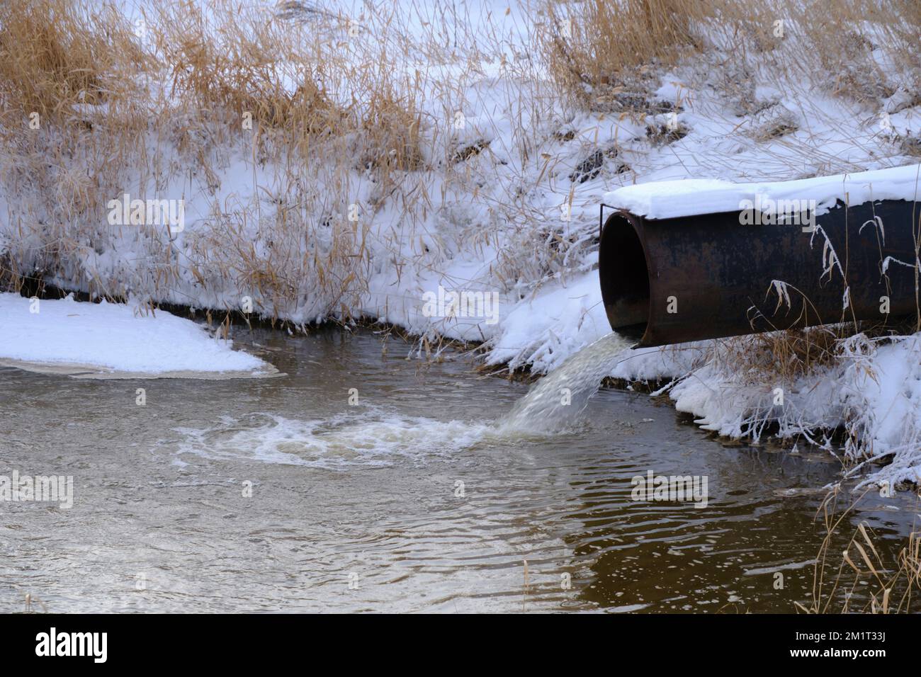 Sewage discharge from pipe into river in winter, river pollution and ...