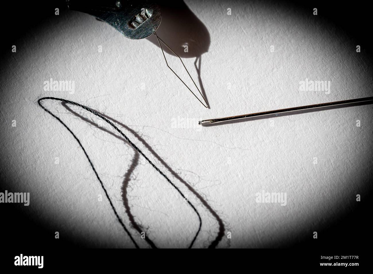 Sewing needle threader tool in use and a single black string Stock ...