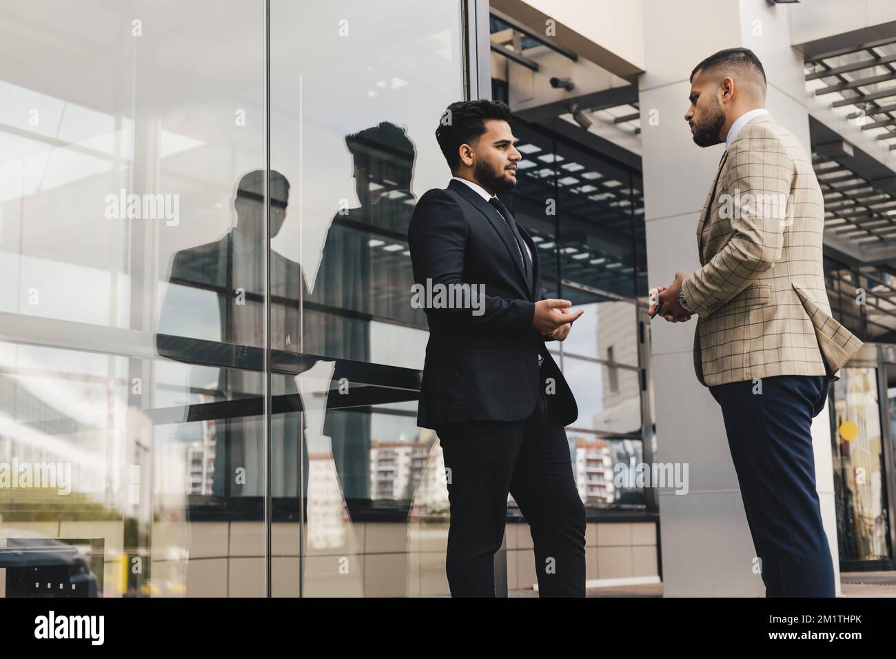 Business people outdoor meeting. Two men in suits are standing and ...