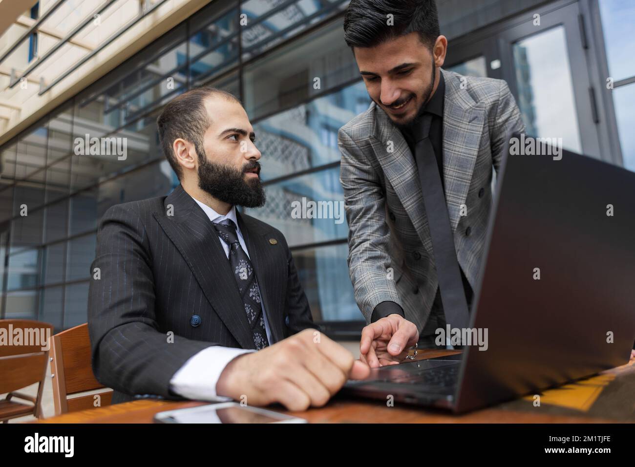 business people meets outdoors. Two men are using a laptop. Working ...