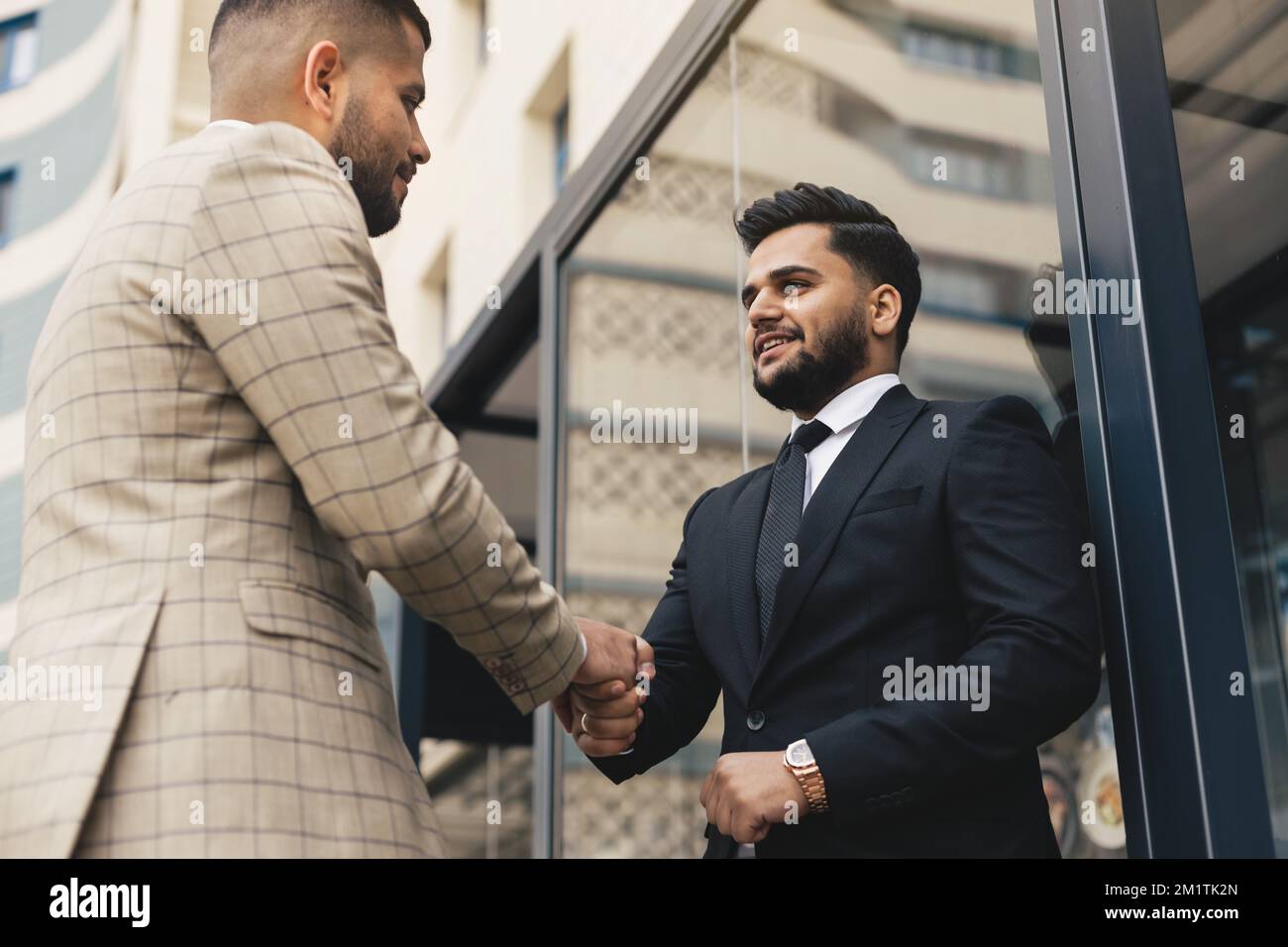 Business people outdoor meeting. Two men in suits hold out their hands ...