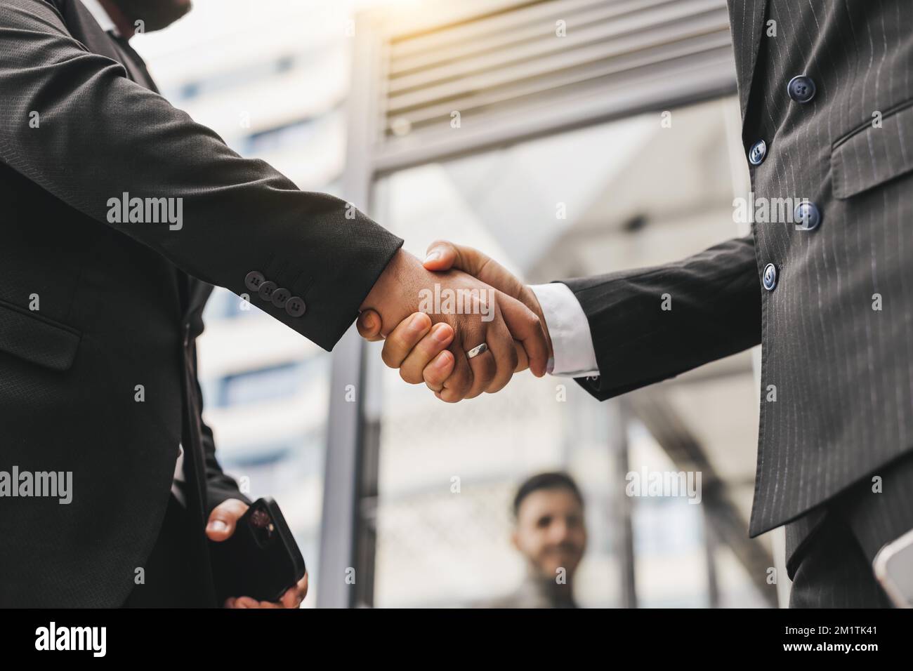 Business people outdoor meeting. Two men in suits hold out their hands ...