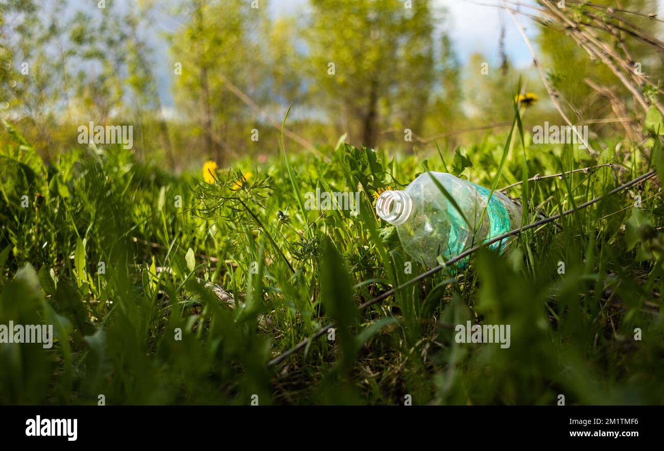 Abandoned garbage plastic and glass waste in nature among the grass ...