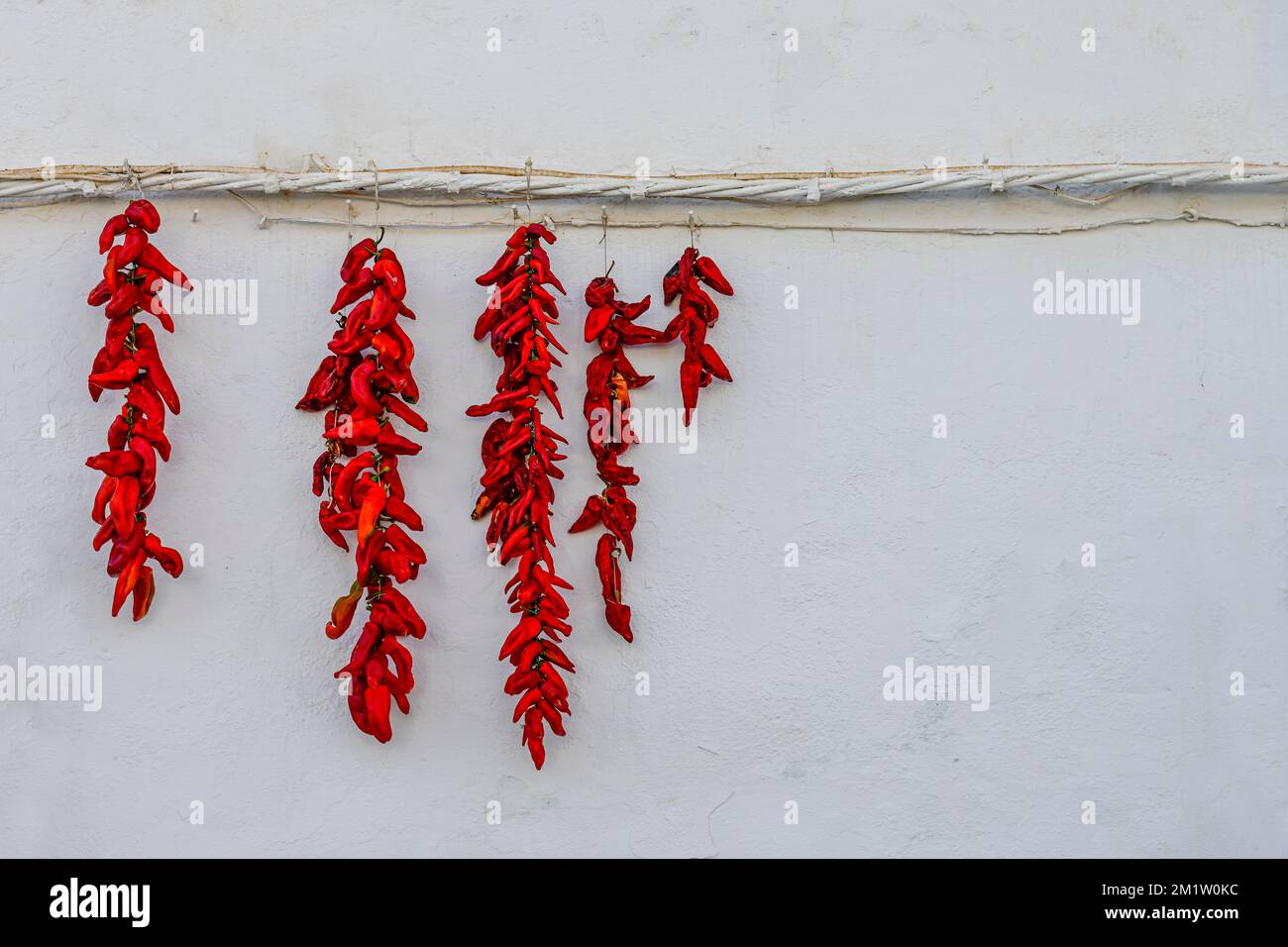 A string of red peppers drying in the sun Stock Photo - Alamy