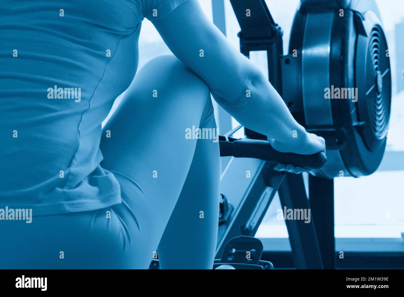 Back view of woman uses a rowing machine Stock Photo - Alamy