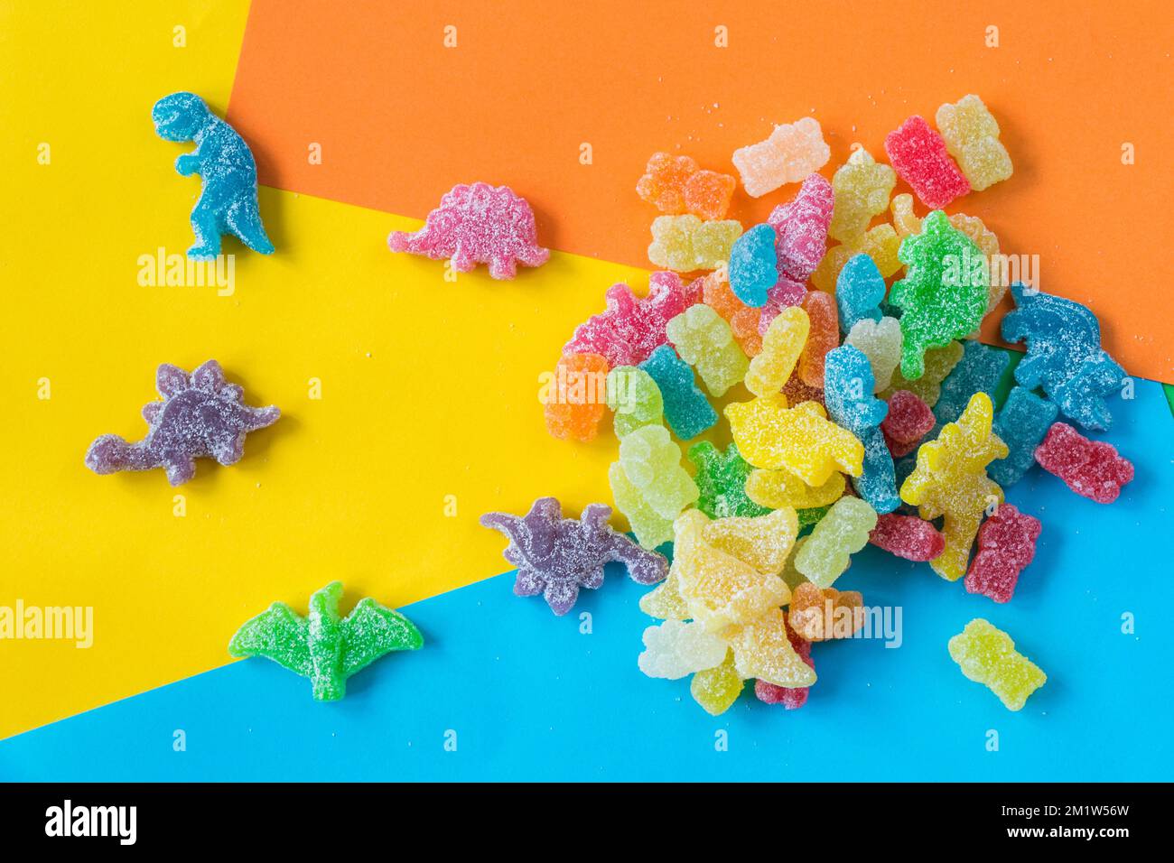 A flat lay of colorful gummy candies in the shape of a dinosaur and a ...
