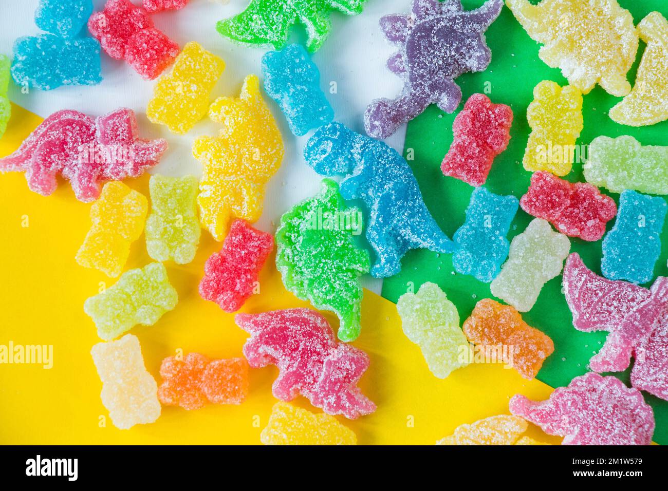 A flat lay of colorful gummy candies in the shape of a dinosaur and a ...