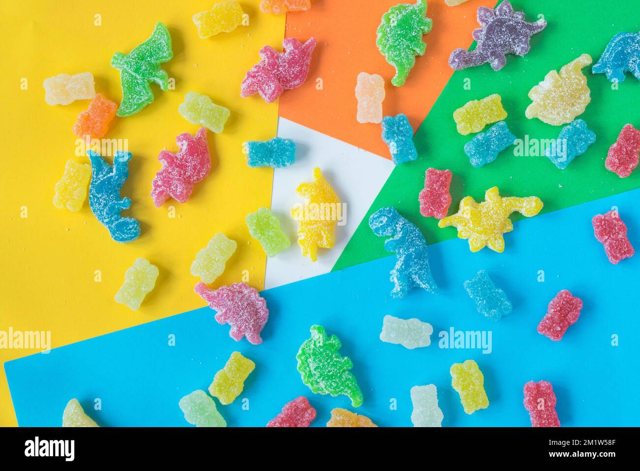 A flat lay of colorful gummy candies in the shape of a dinosaur and a ...
