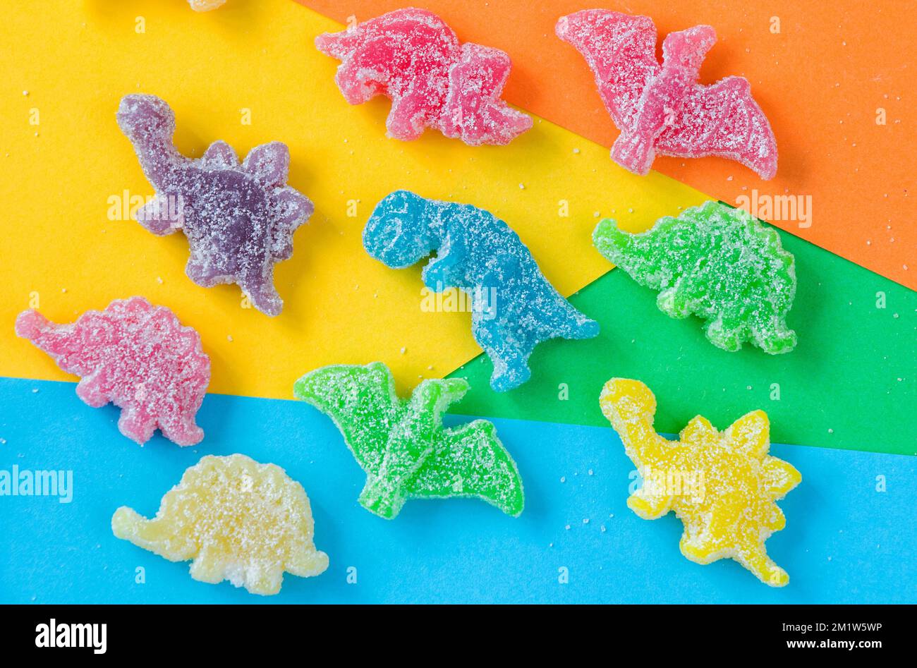 A flat lay of colorful gummy candies in the shape of a dinosaur and a ...