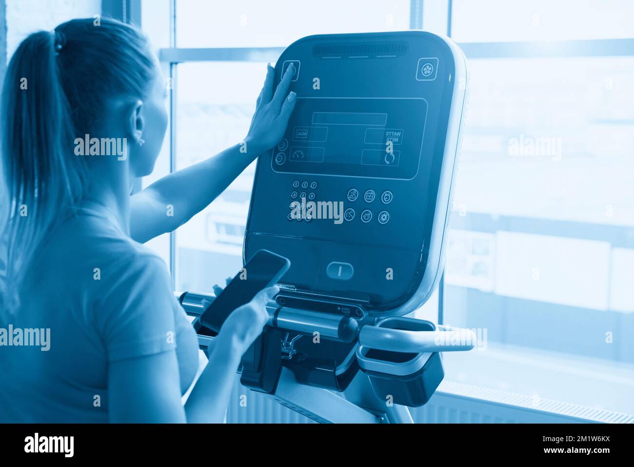 Woman adjusting settings on training machine in gym Stock Photo - Alamy