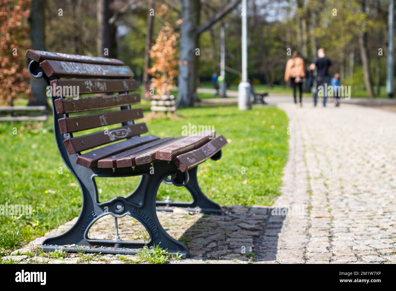 A bench at the Stromovka Royal Park with a family walking on the ...