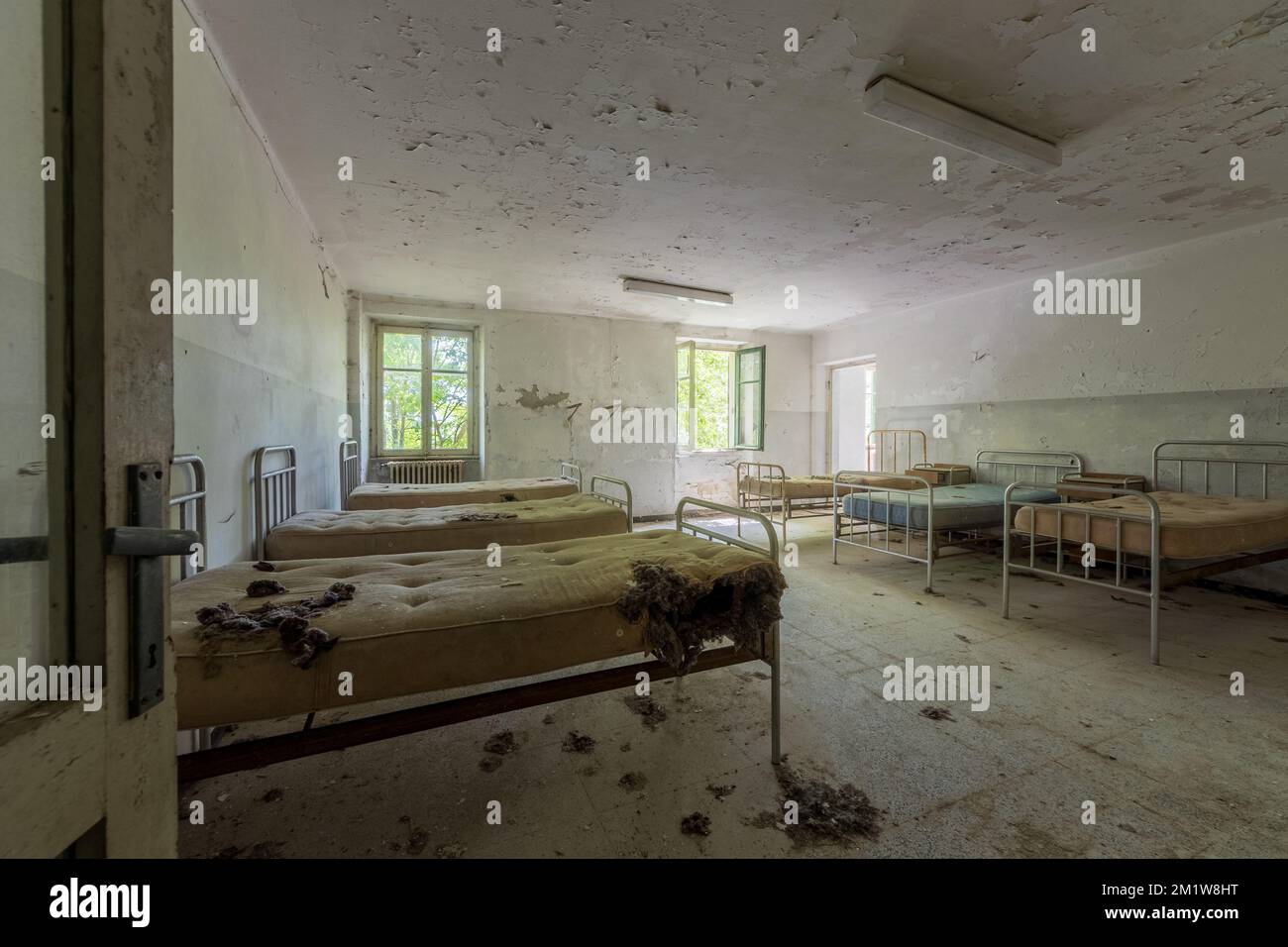 An old abandoned and dilapidated hospital with many beds with windows ...