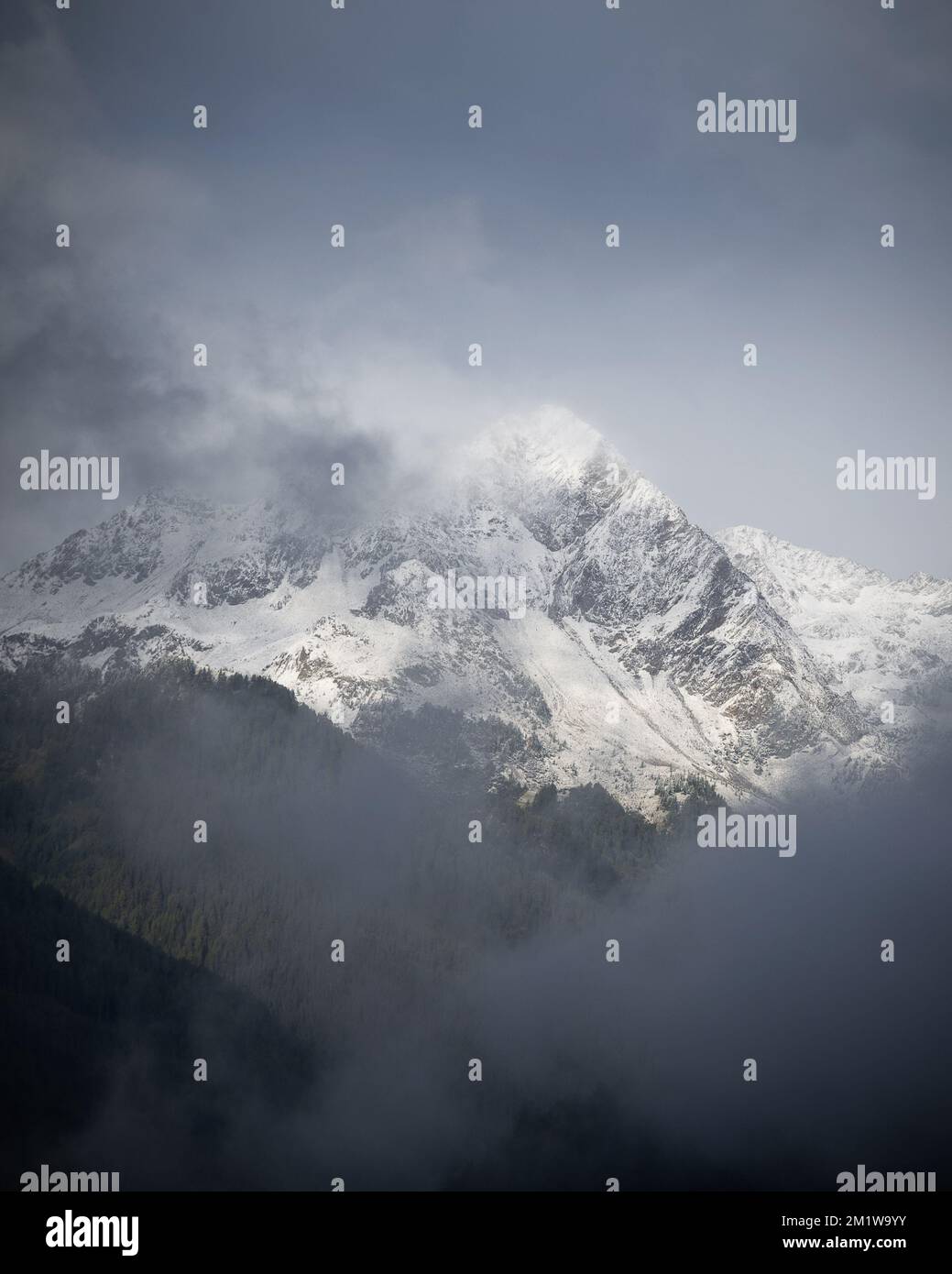 A vertical shot of a breathtaking snowy mountain covered in fog Stock ...