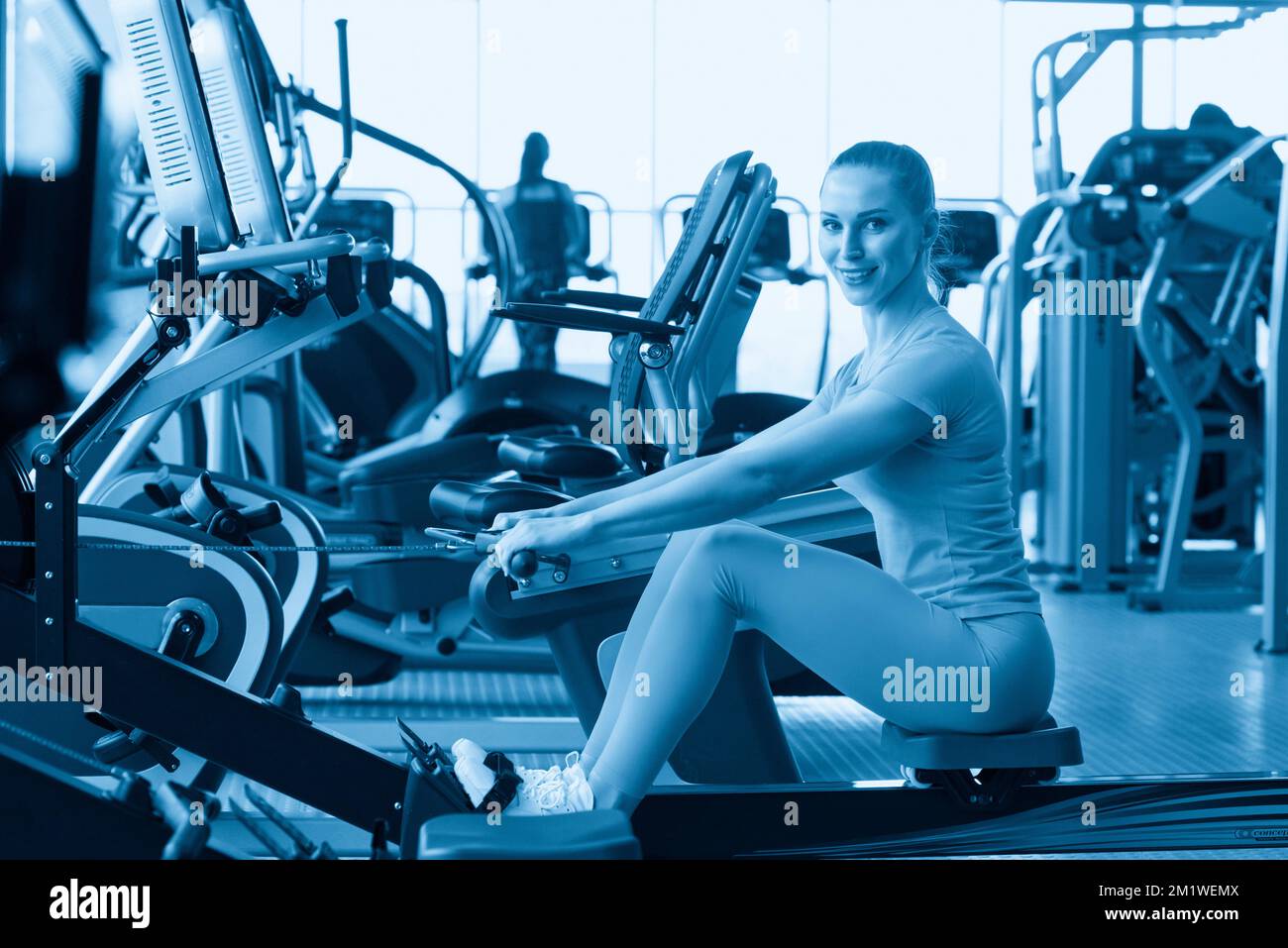 Side view of fit young women using rowing machine in health club Stock ...