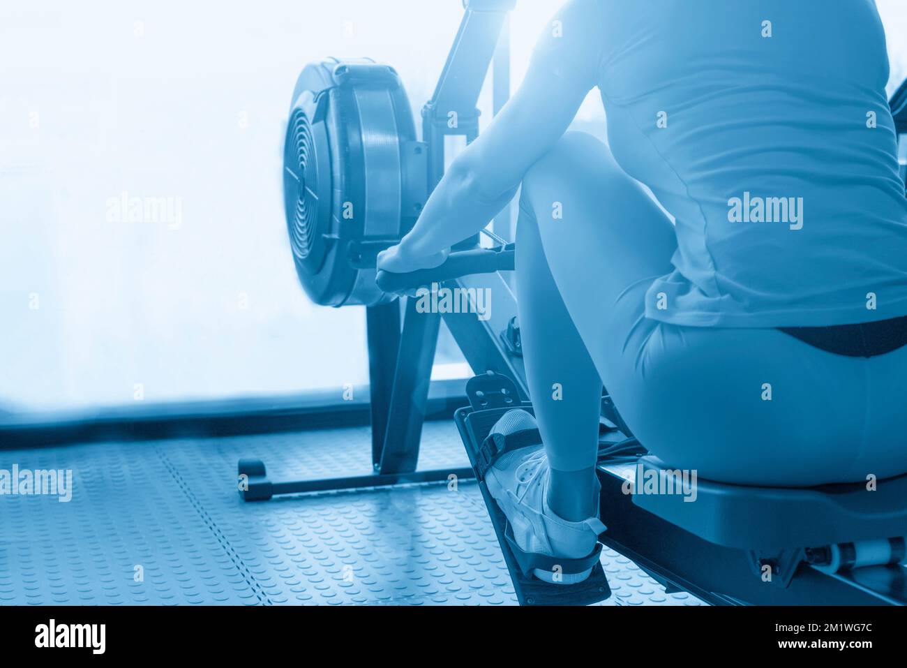 Back view of woman uses a rowing machine Stock Photo - Alamy