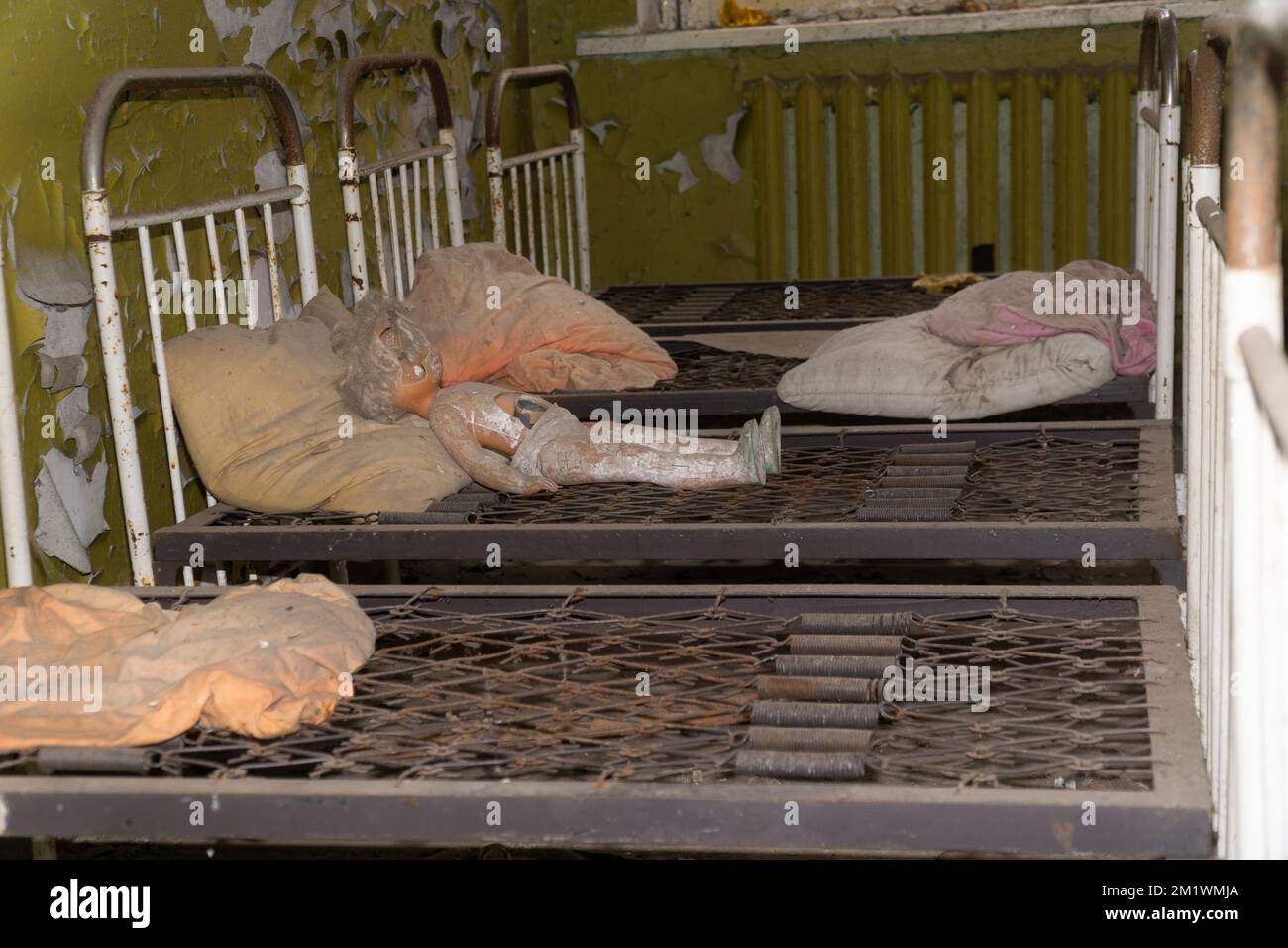 An old doll over a rusty bed with old pillows inside an abandonated ...