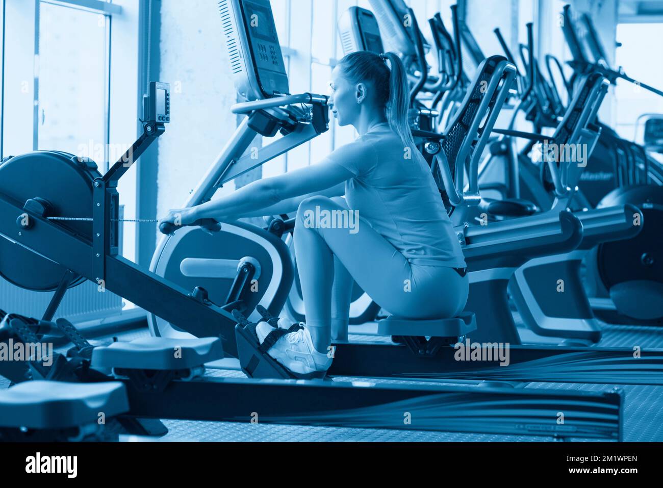 Side view of fit young women using rowing machine in health club Stock ...