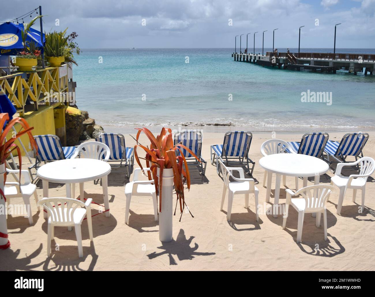 Tables and chairs in sunlit cafe on Barbados beach Stock Photo - Alamy