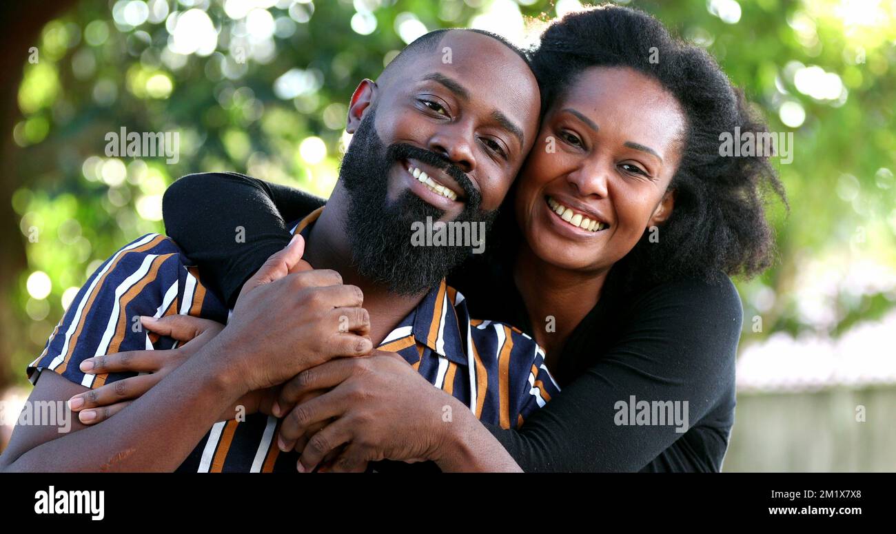African couple in love embrace and hug outside looking at camera, two ...