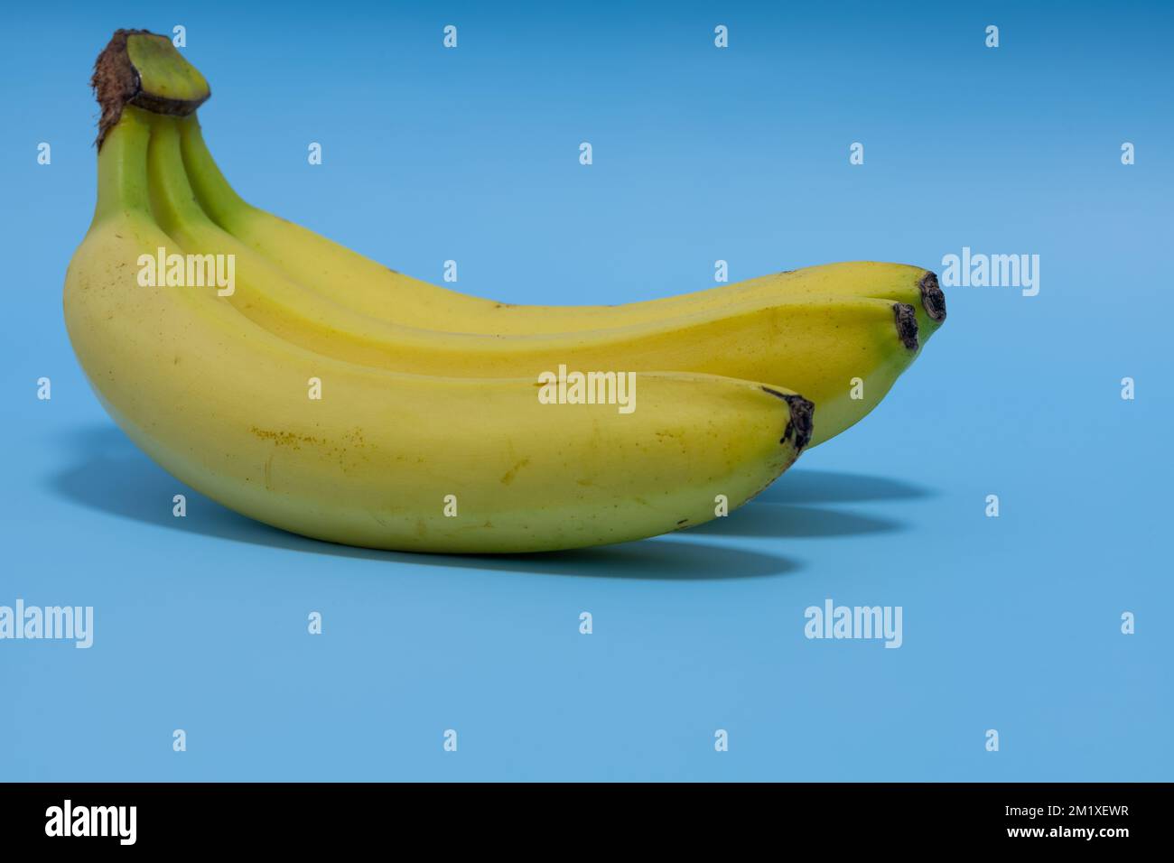 A bunch of bananas on a blue background Stock Photo - Alamy