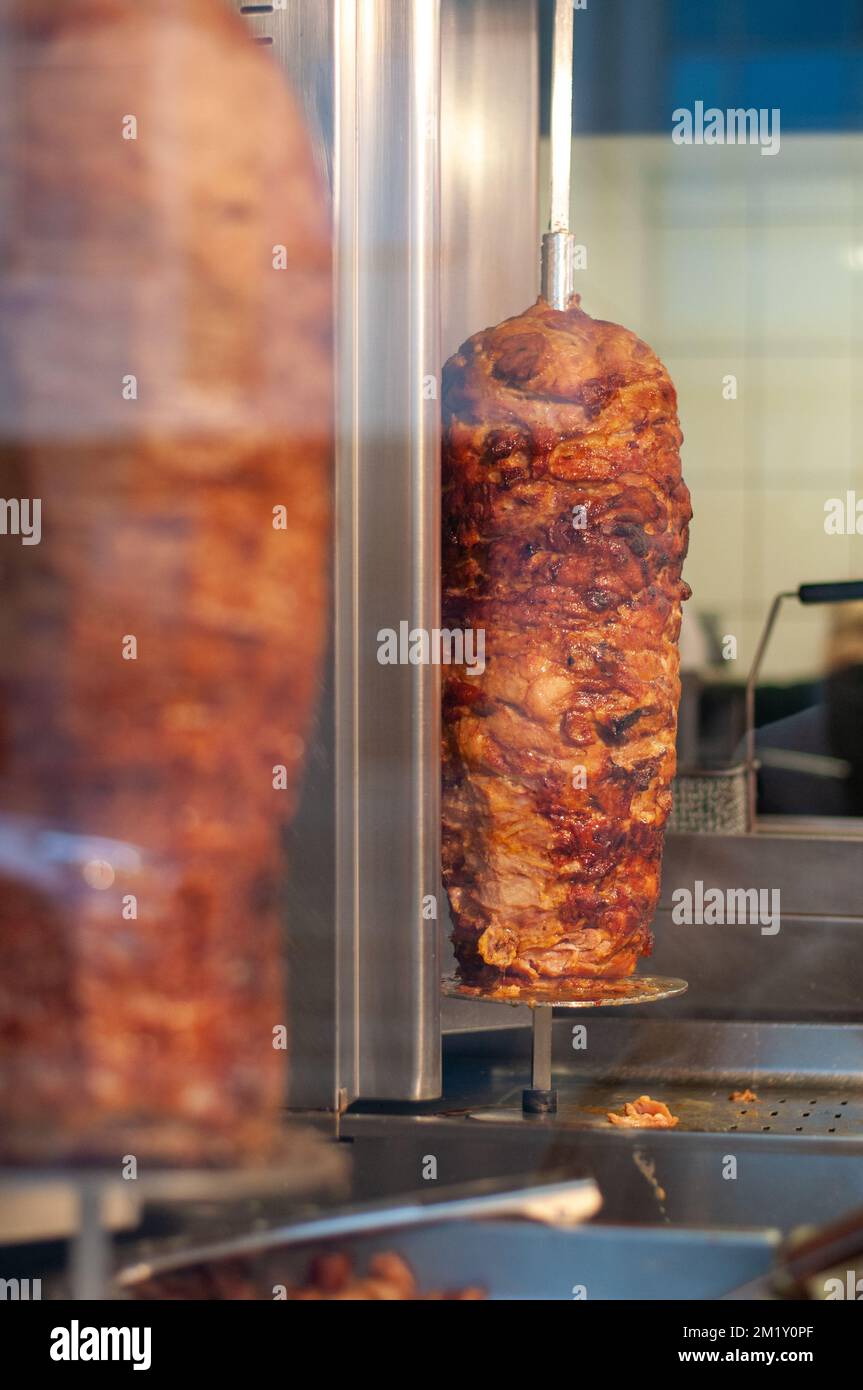 A vertical closeup of grilled skewered chicken on the spit in a kitchen ...
