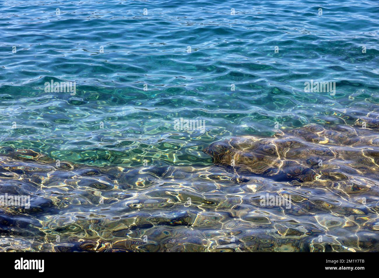 Transparent sea surface with stones on a bottom. Rocky beach, turquoise ...