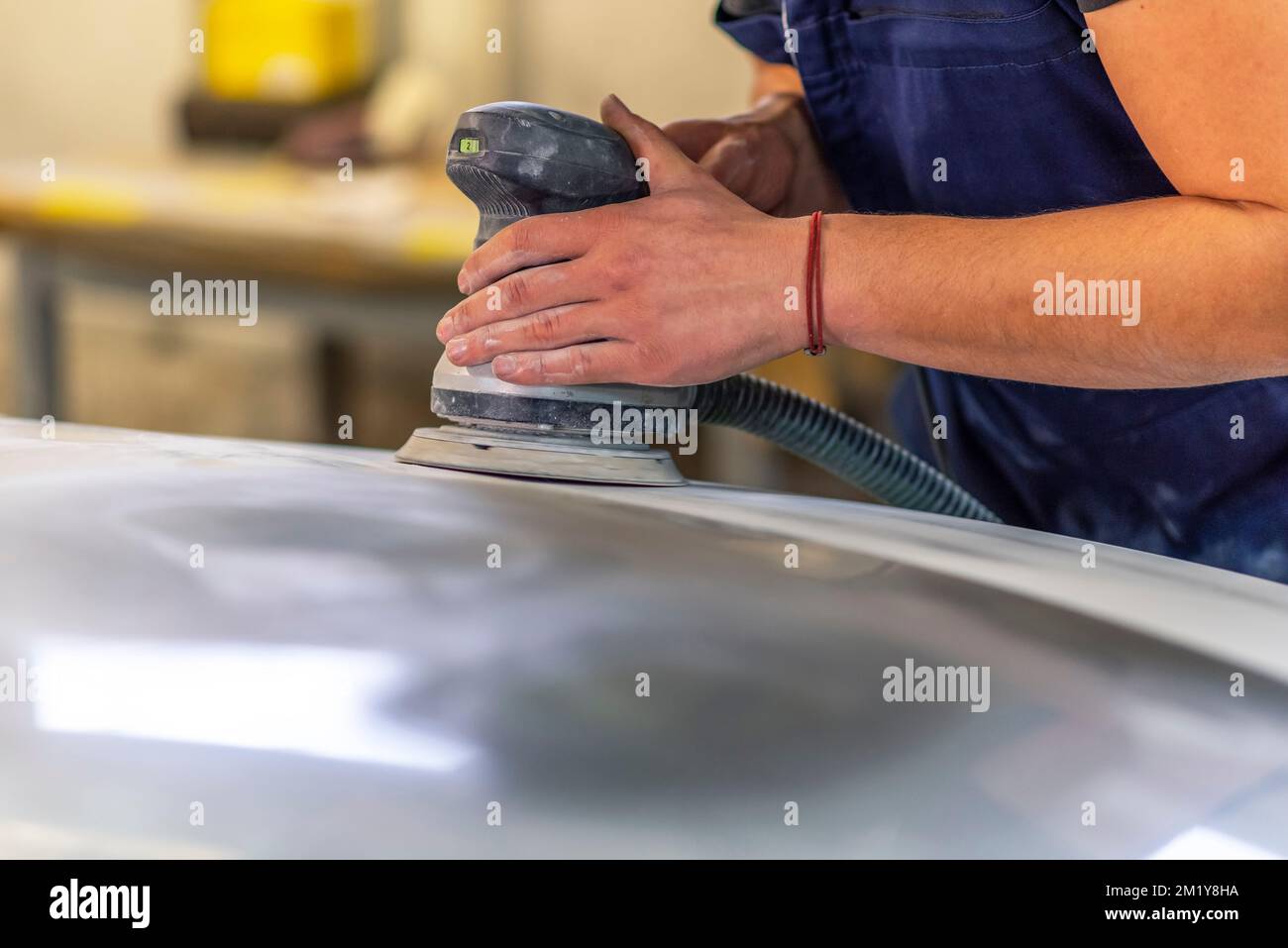 Grinder in the hands of a man who sharpen a car varnish in the car shop ...