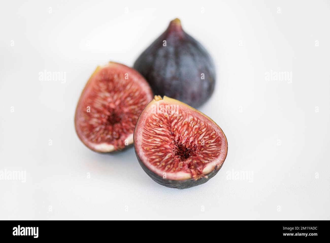 Isolated Black mission figs, one whole and one halved, positioned on a ...