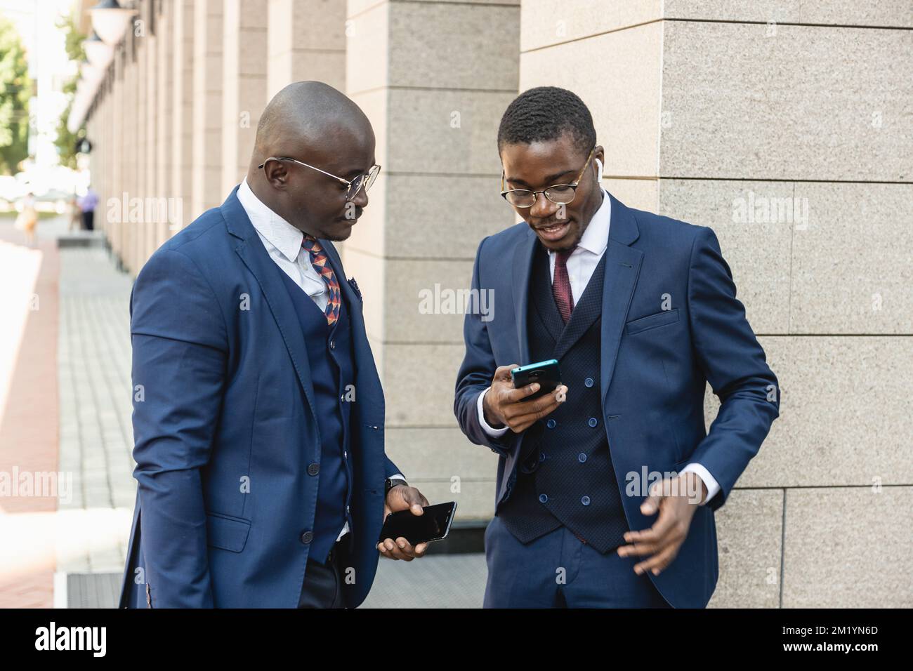 A couple of black African American businessmen friends in suits are ...