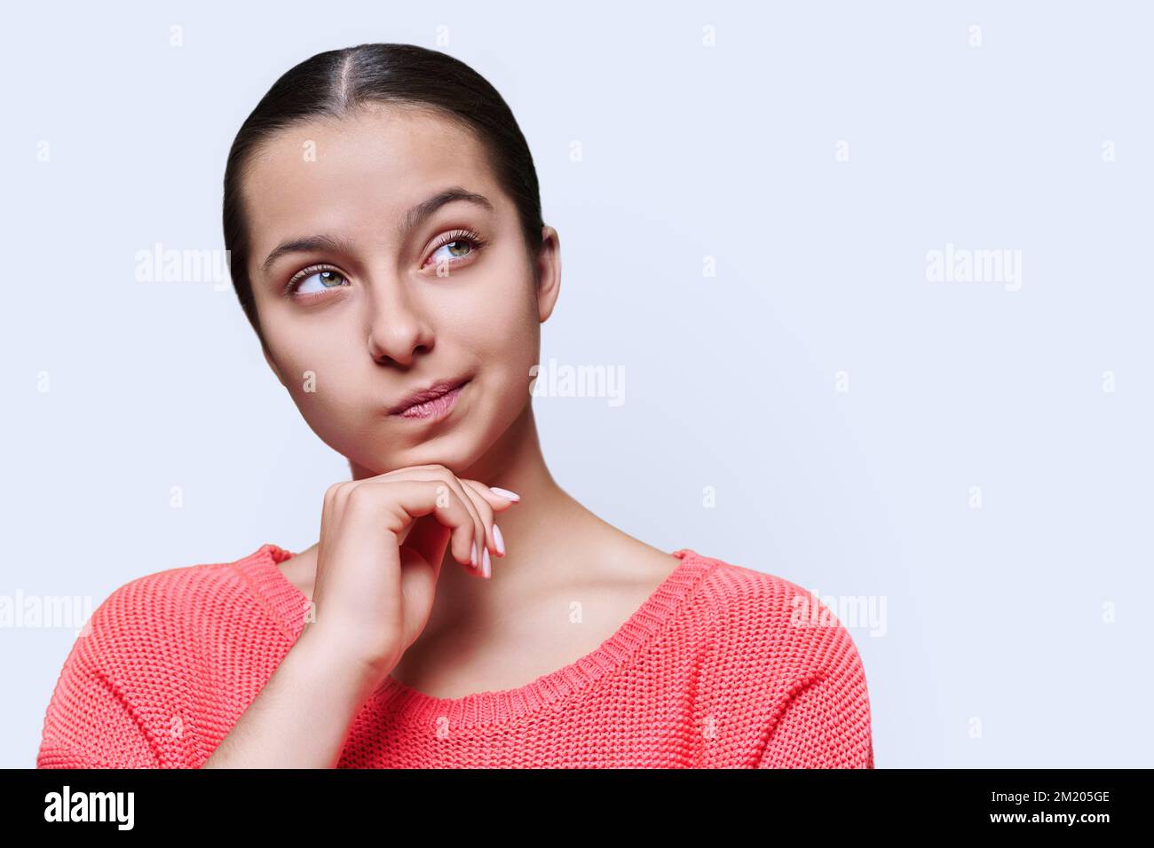 Pensive teenage female dreamily looking away, white studio background ...