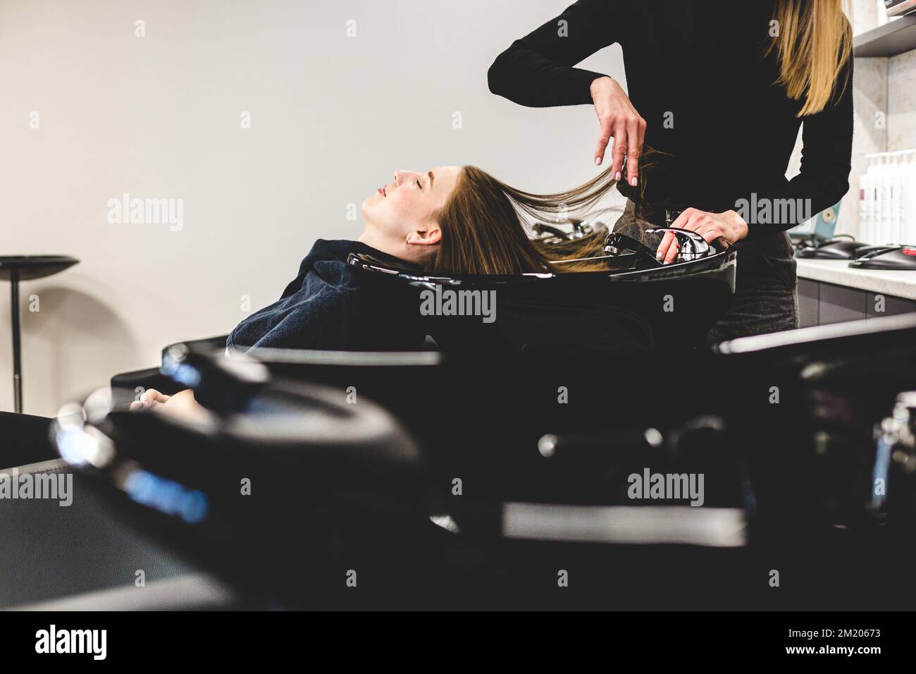 Master woman hairdresser gently washes the girl's hair with shampoo ...