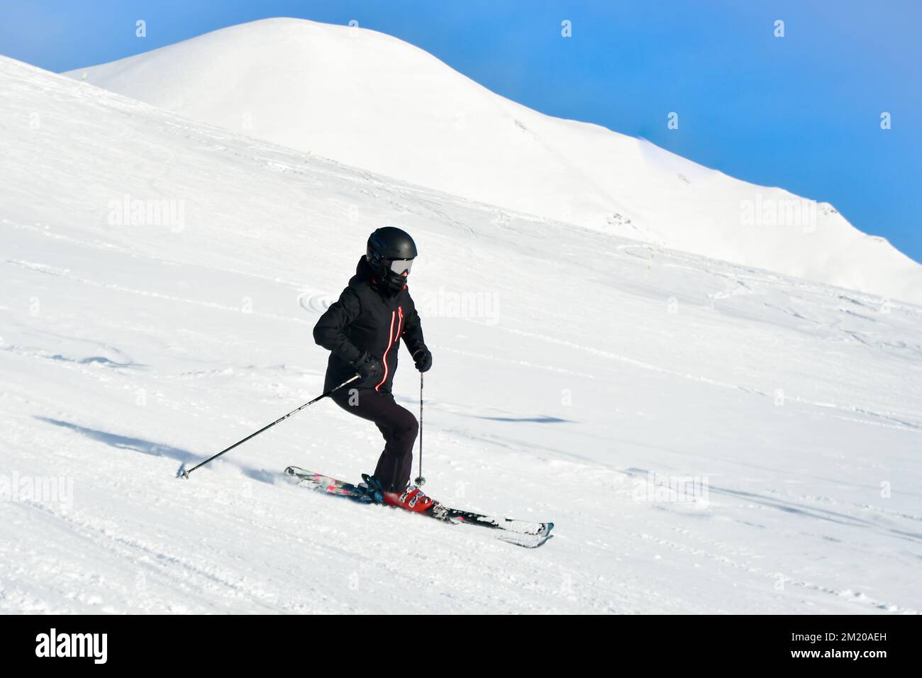 Cool female skier in black close up side view go downhill carving fast ...