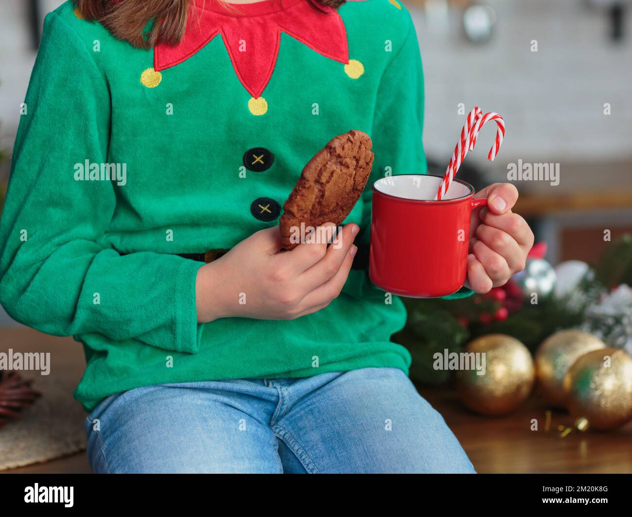 Cute little elf child girl eating chocolate biscuits and drinking hot ...