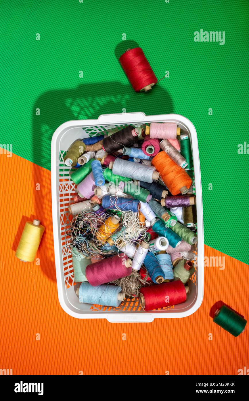A box with multi colored coins of different threads on a colored ...