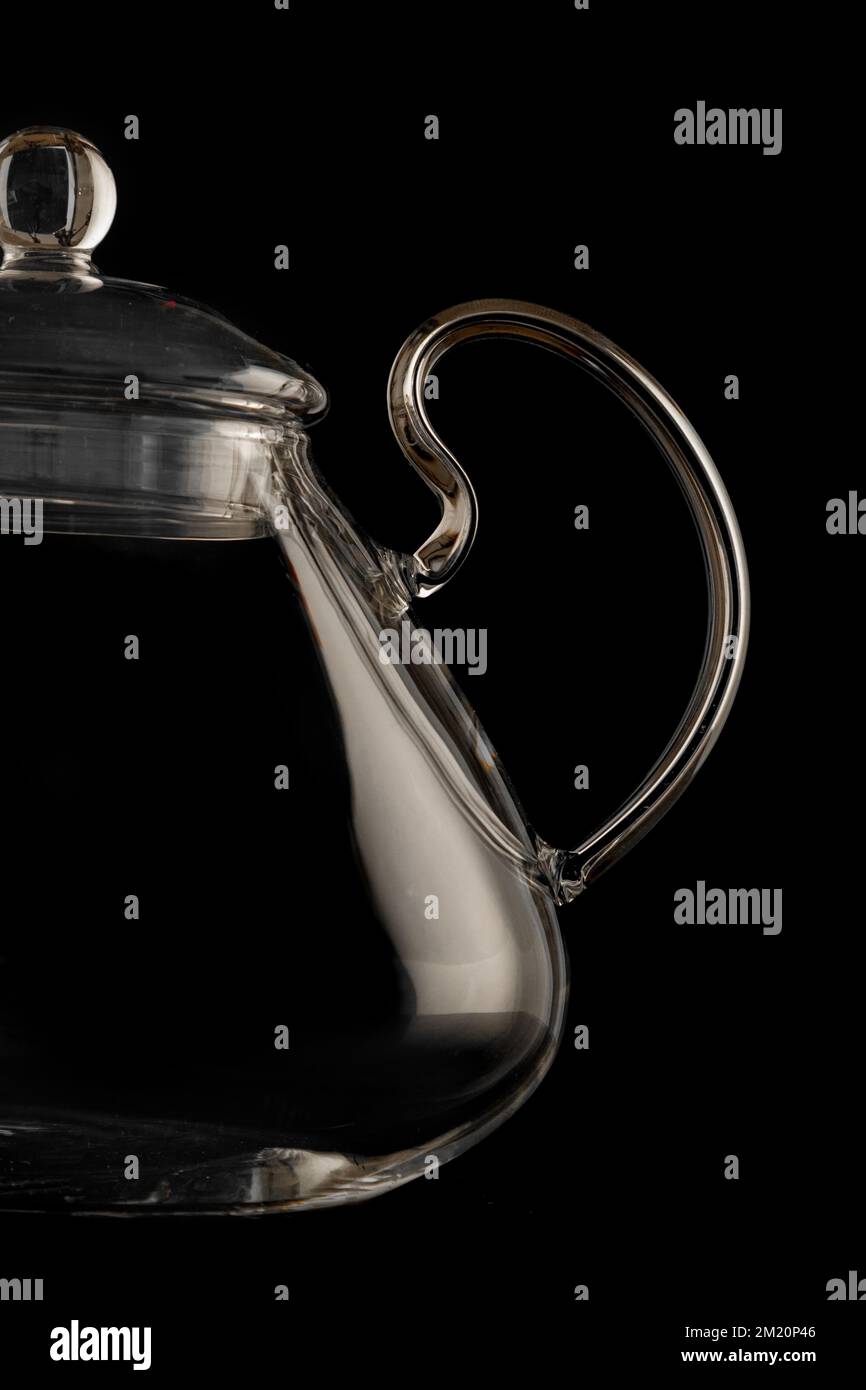 Beautiful transparent glass teapot handle close-up isolated on black ...