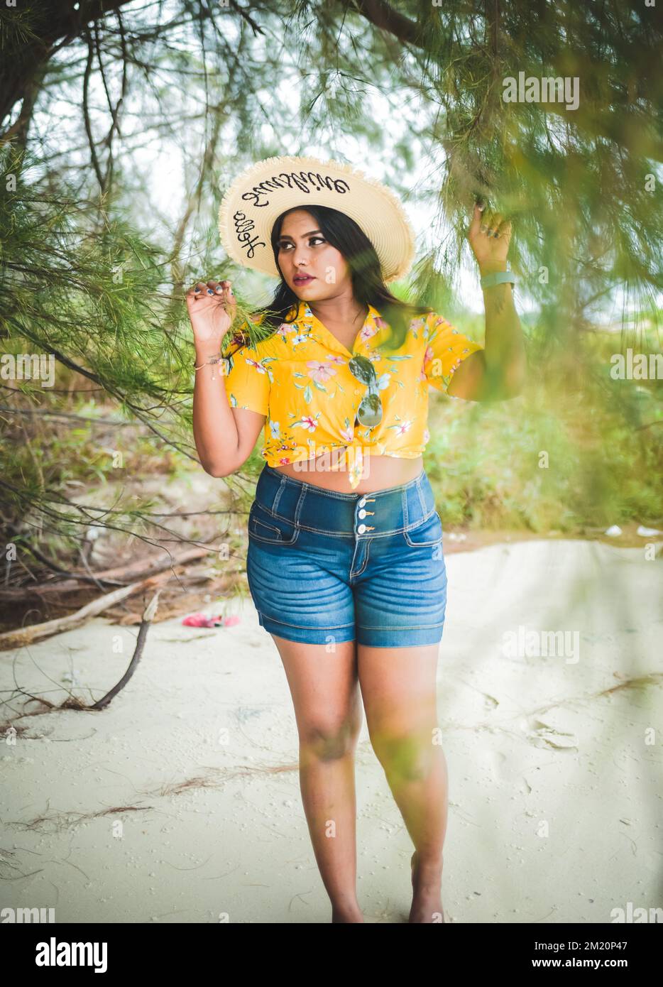 A vertical of a South Asian female in a floral yellow shirt and shorts ...