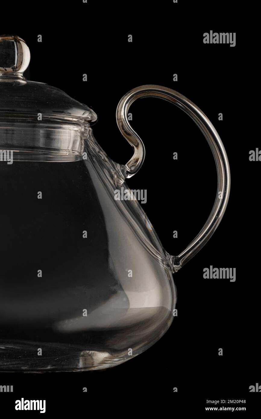 Beautiful transparent glass teapot handle close-up isolated on black ...