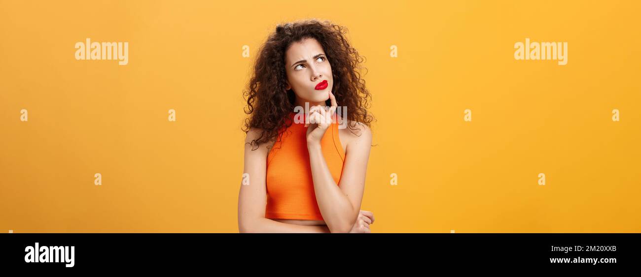 Waist-up shot of perplexed thoughtful and smart female with curly ...