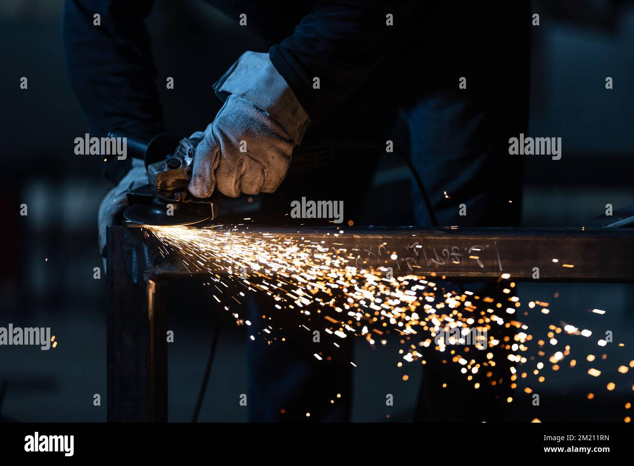 Man working on iron with grinder. Man at work. Sparkles and fire from ...