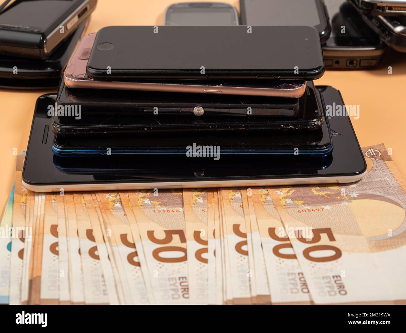 Lots of old smartphones and money on an orange background. Old mobile ...