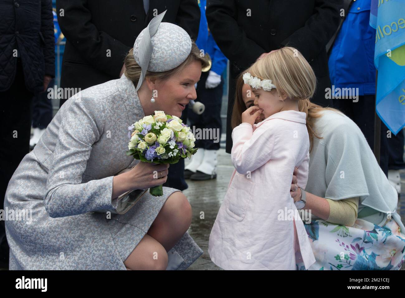 Queen Mathilde of Belgium (L) receives flowers from a child at the ...