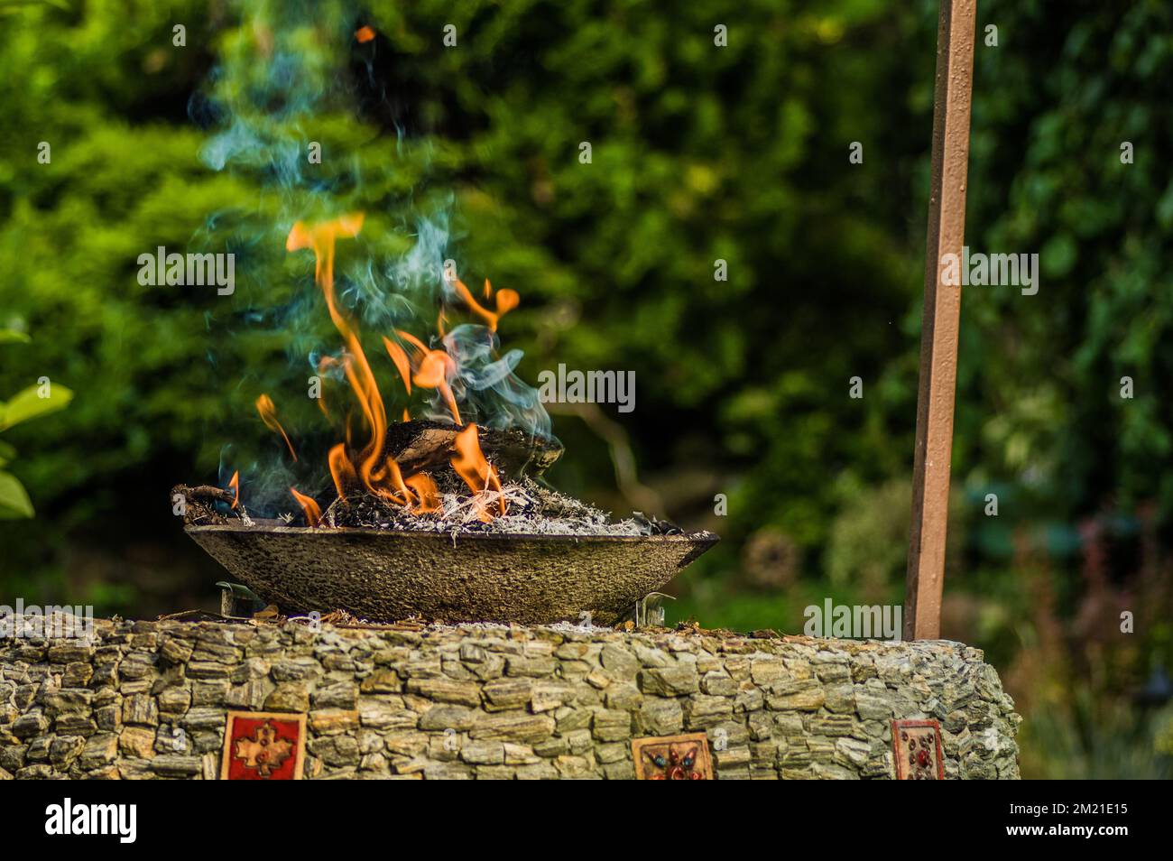 A selective focus shot of dry plants burning in a bowl in a garden ...