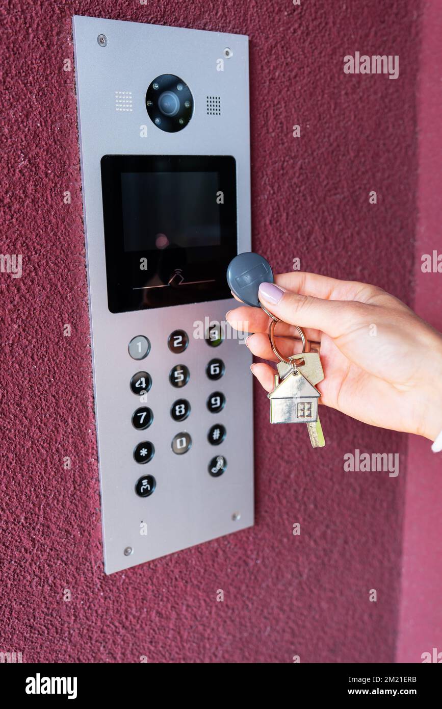 A young woman types the apartment code on the electronic intercom panel ...