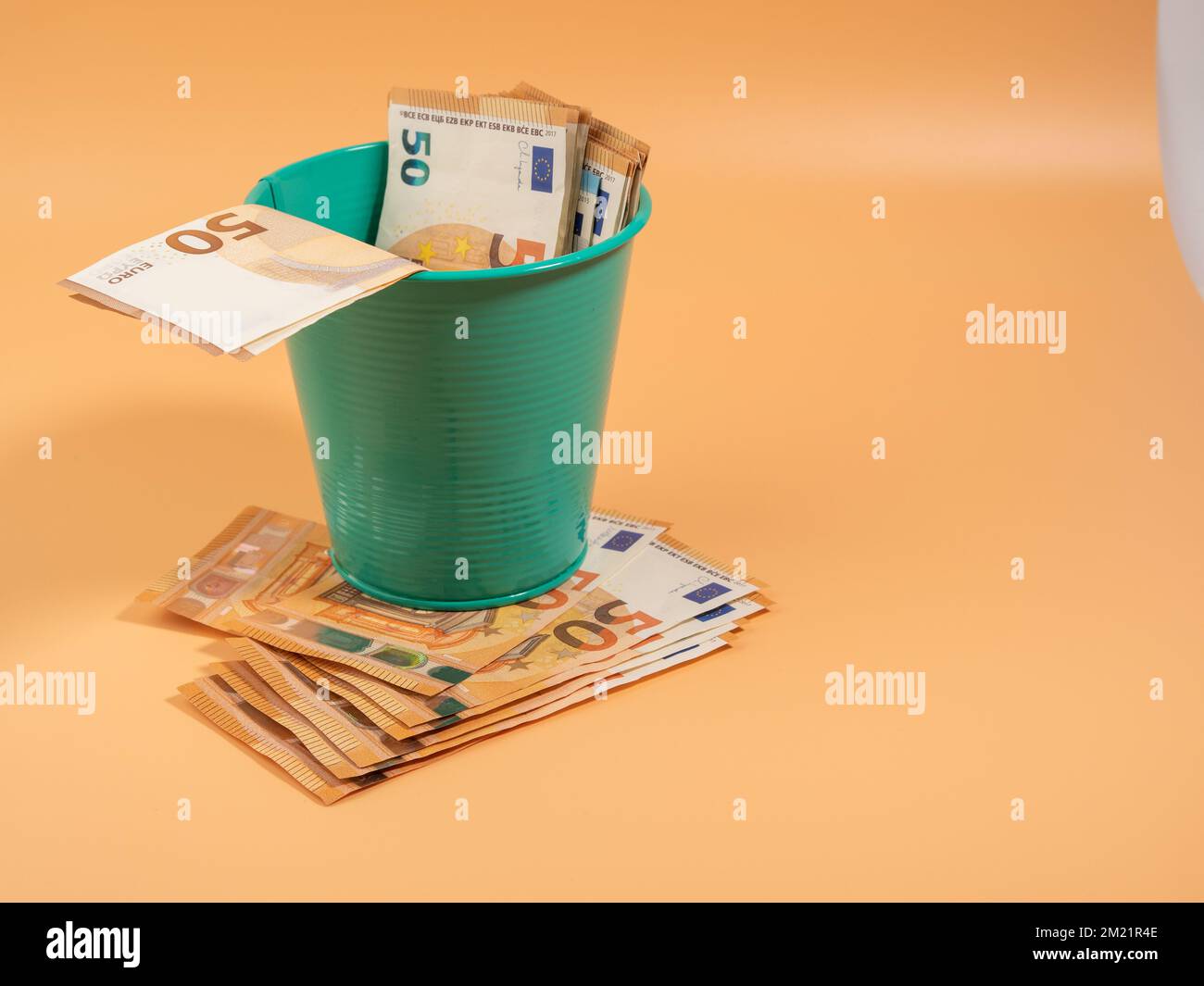 Money in the trash can on an orange background. Euros in the trash ...