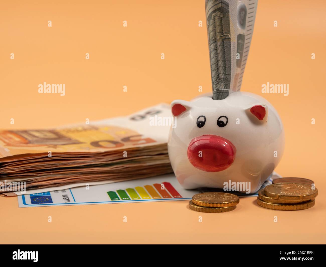 Money, piggy bank and energy efficiency certificate on orange ...